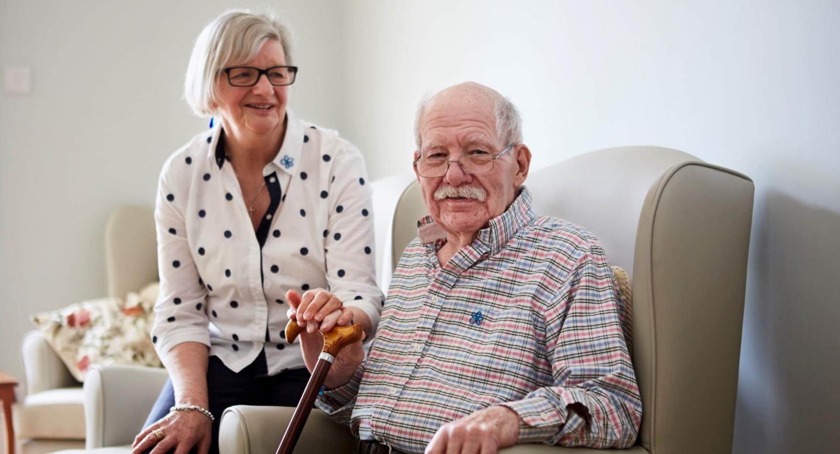 A man with dementia sitting with his carer. | Alzheimer's Society